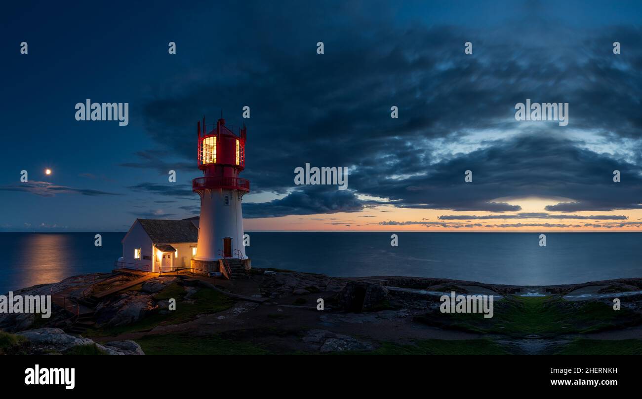 Lighthouse surrounded by rocks at night, lighthouse with lights on at ...