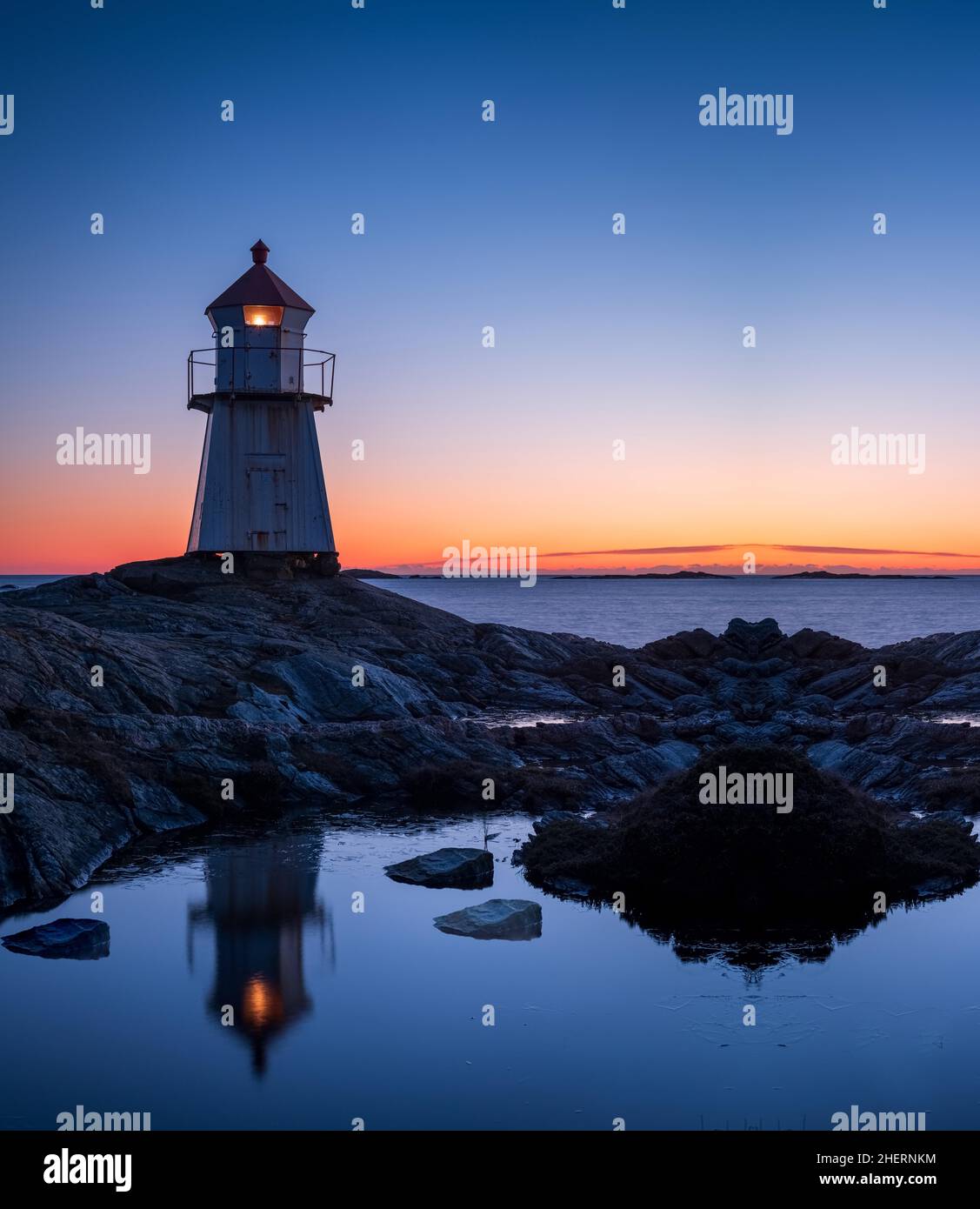 Lighthouse surrounded by rocks at night, lighthouse with lights on at ...