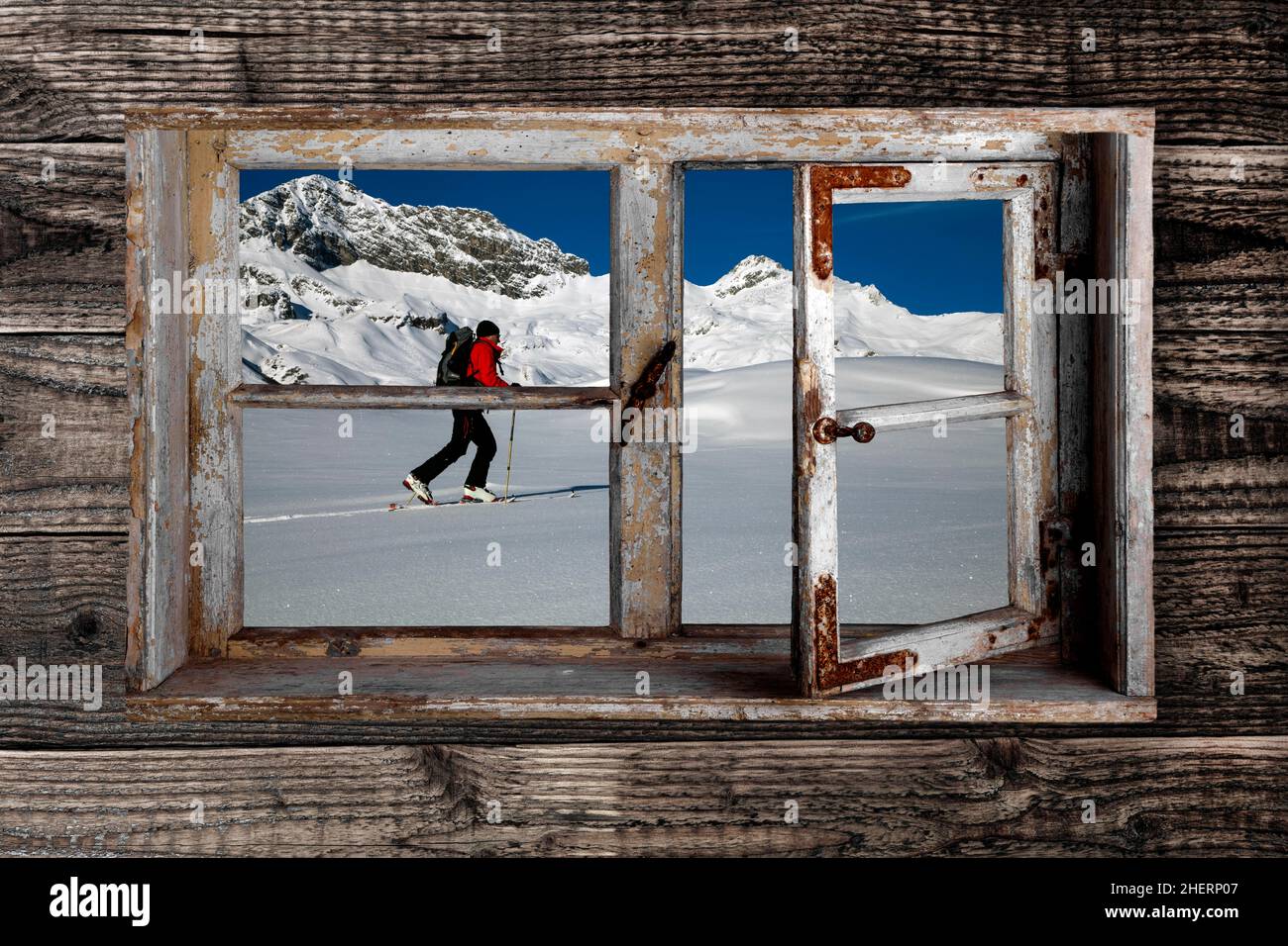 View through a rustic wooden window of a touring skier, Lech am Arlberg ...