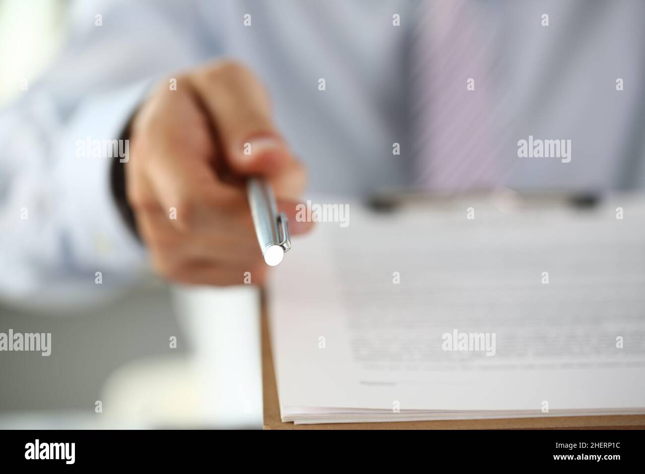 Man hand holds out pen to sign contract Stock Photo - Alamy