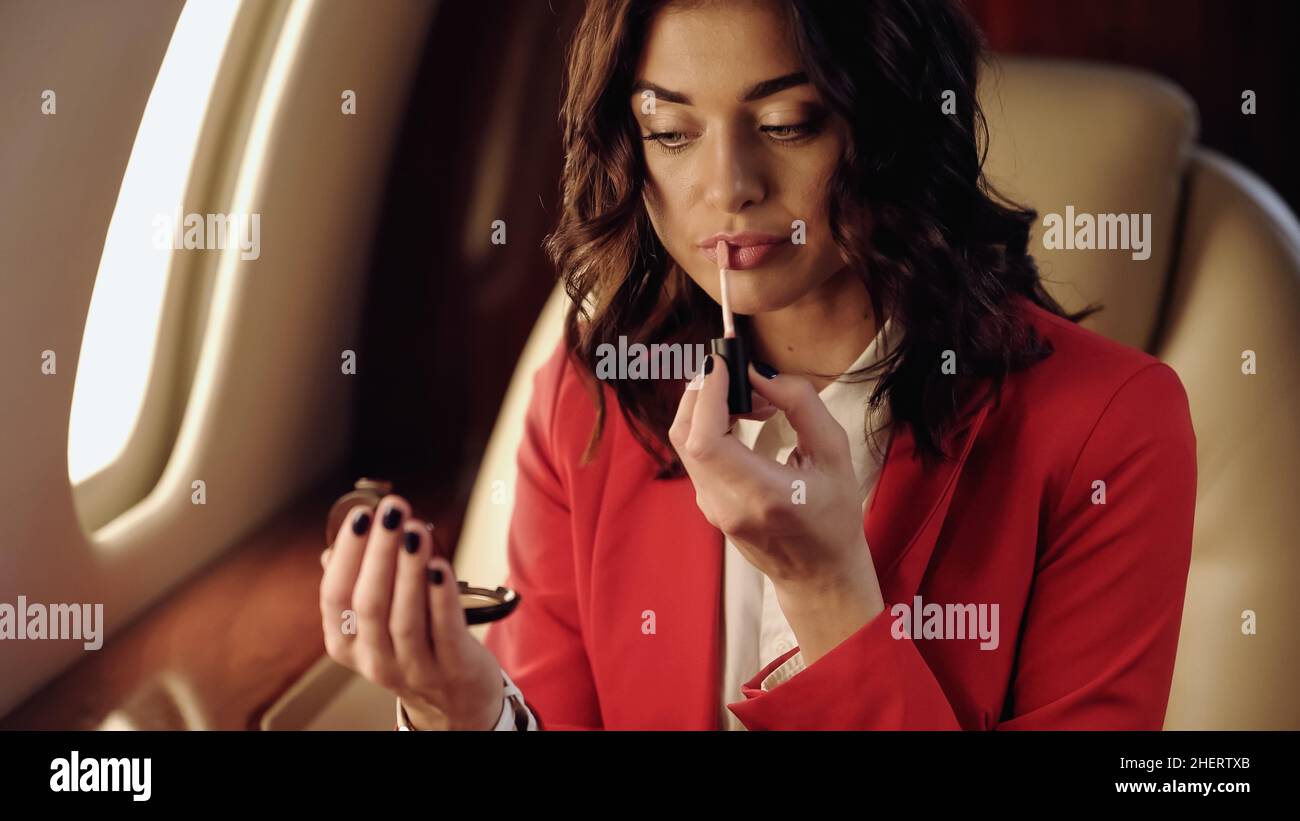 Businesswoman applying lip gloss in private airplane Stock Photo - Alamy