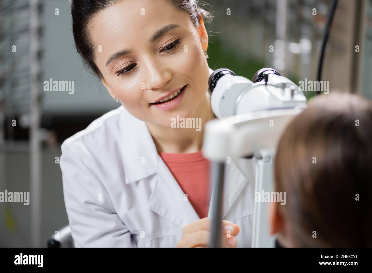 positive optometrist checking eyesight of girl on autorefractor in ...