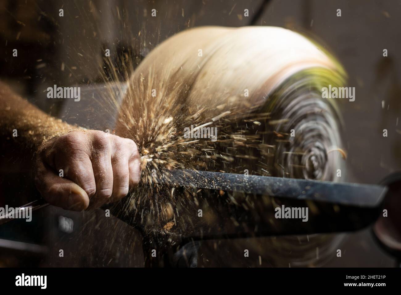 flying wood shavings while cutting and carving wooden bowl on turnery ...