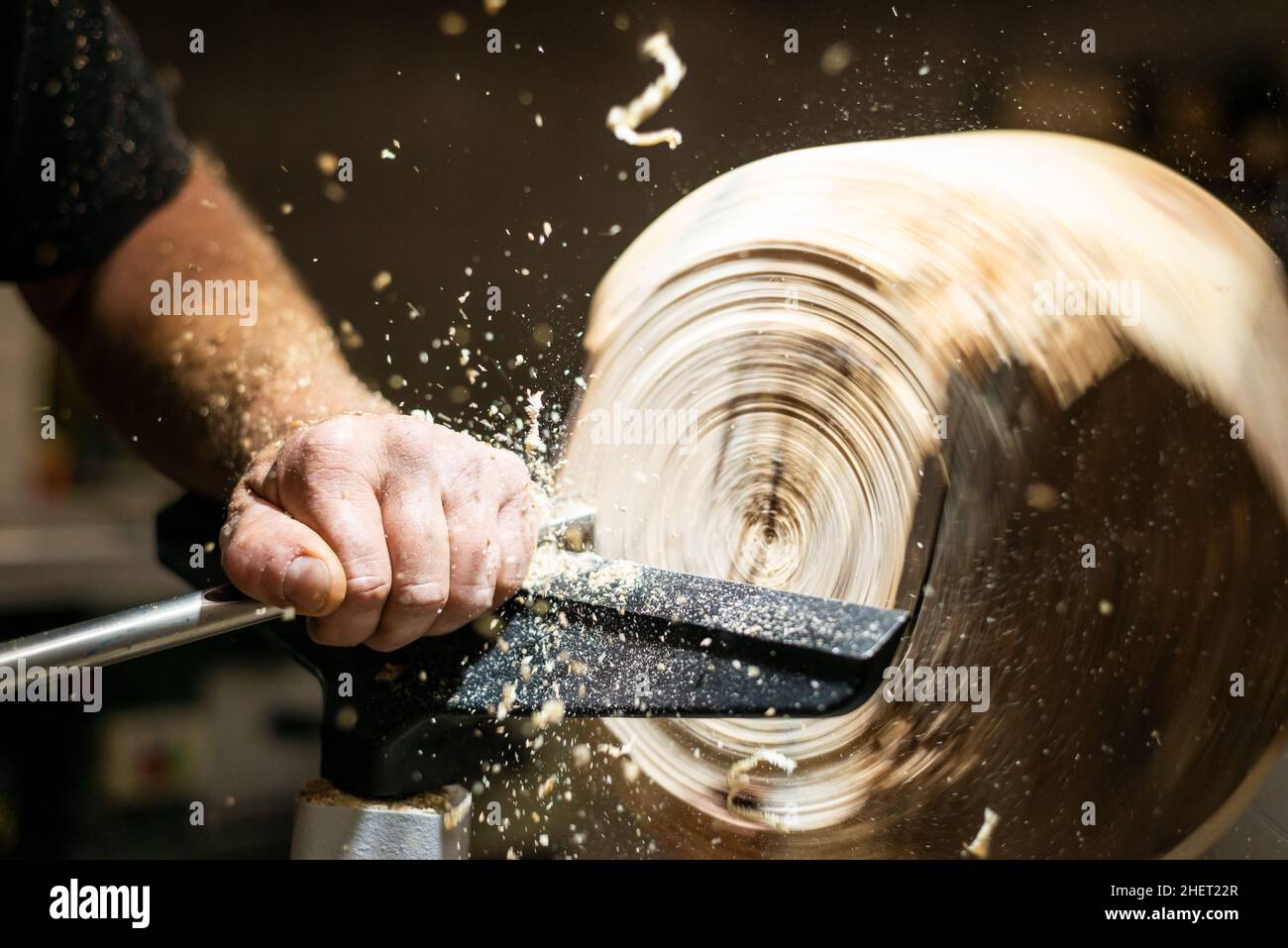 wood working hand edits roating timber with turnery and flying sawdust ...