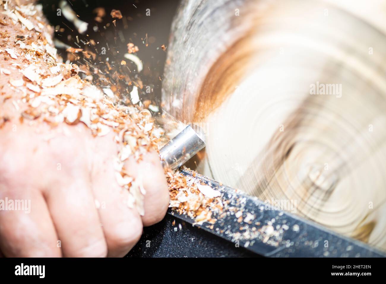 closeup of rotating wood and hand with turnery and flying sawdust ...