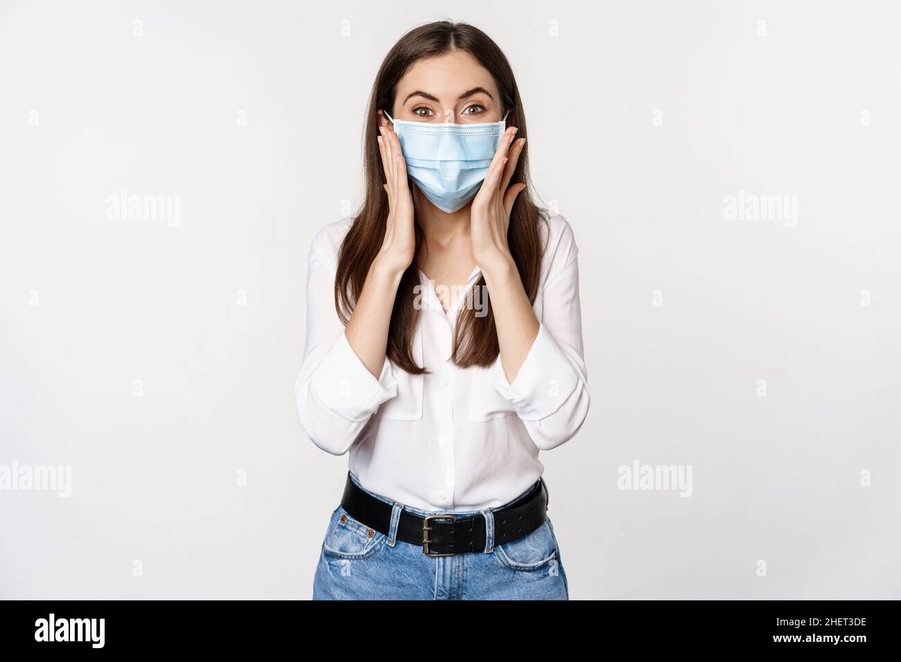 Surprised woman in face medical mask looking amazed, checking out ...