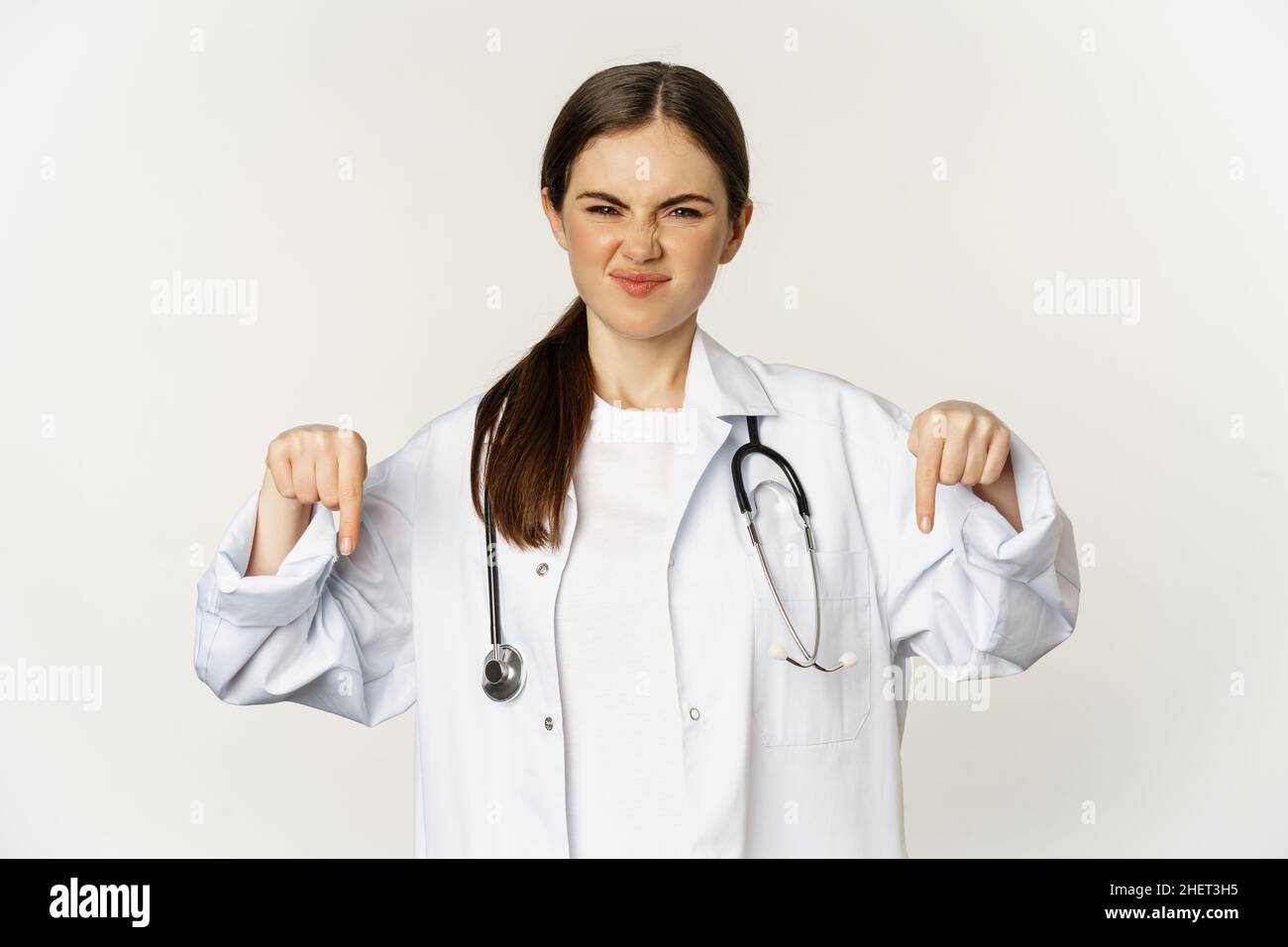 Disappointed young doctor, female physician pointing fingers down and ...