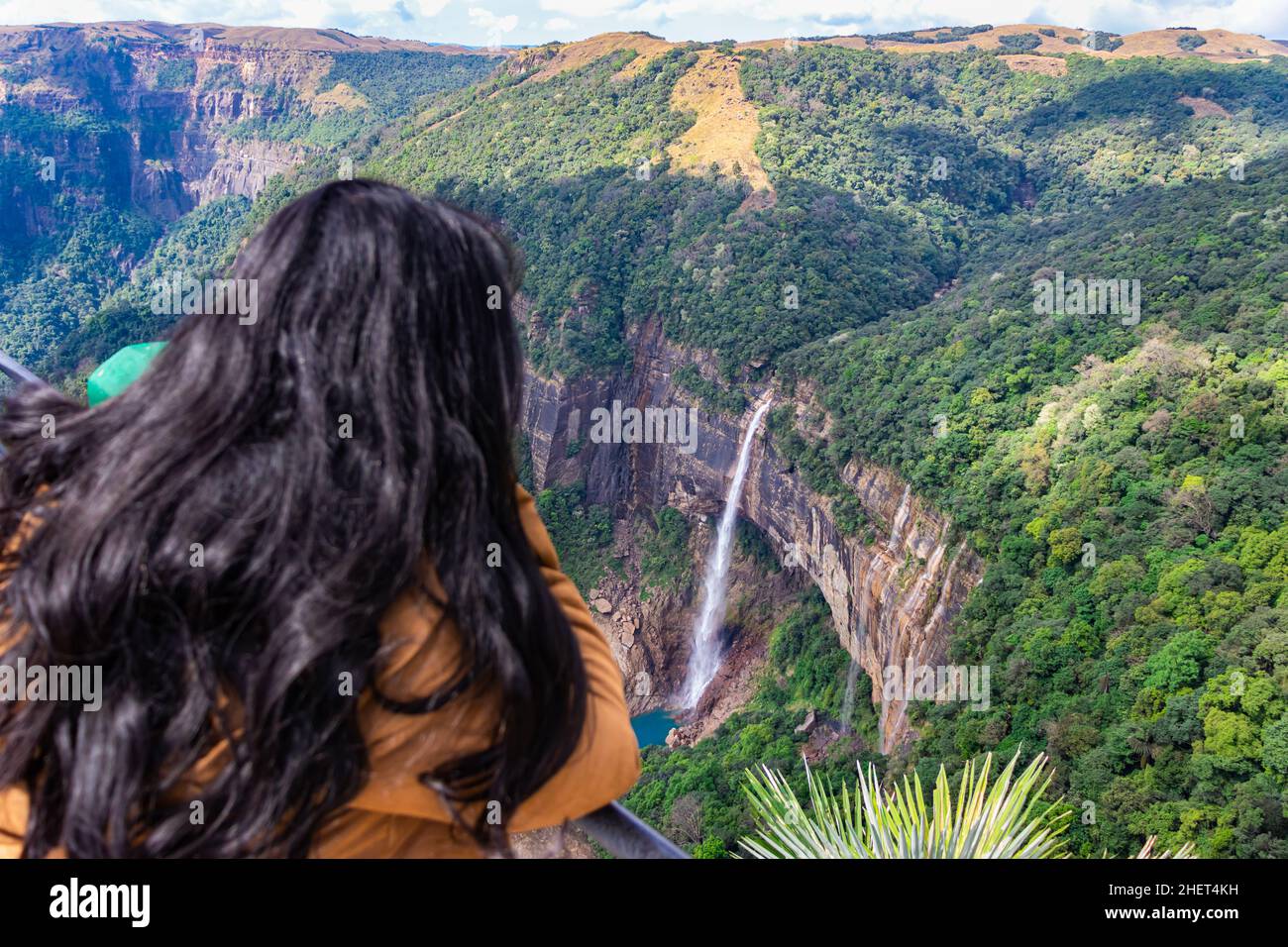 young girl watching waterfall streams falling from mountain top covered ...