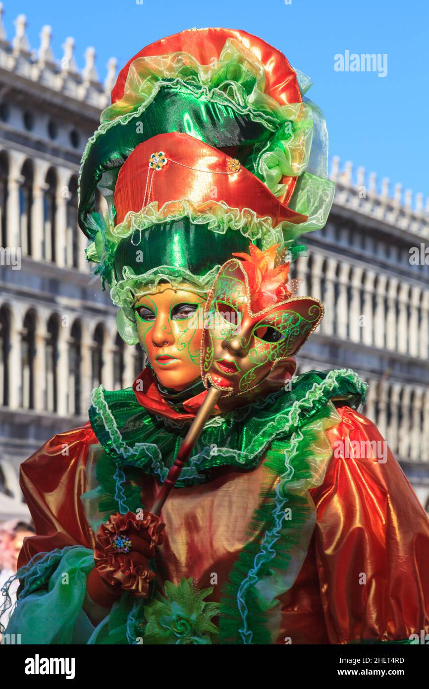 Woman in colourful historic Venetian fancy dress costume. hat and mask ...