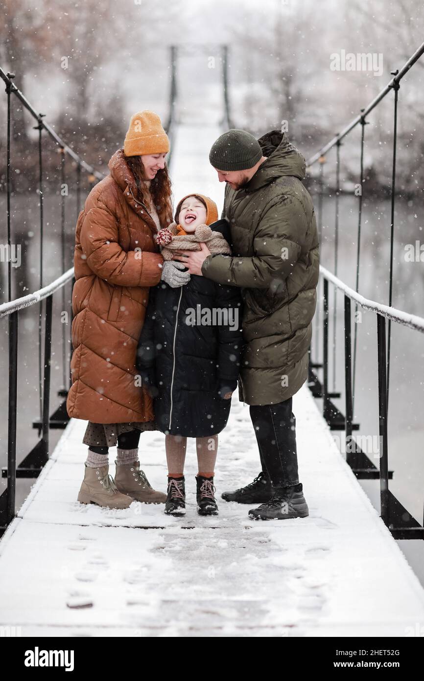 Young mother, father and the little daughter catches snowflakes in a ...