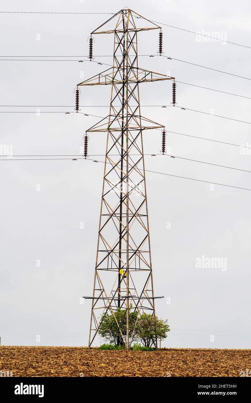 Single electricity pylon on the horizon in a brown field with two ...
