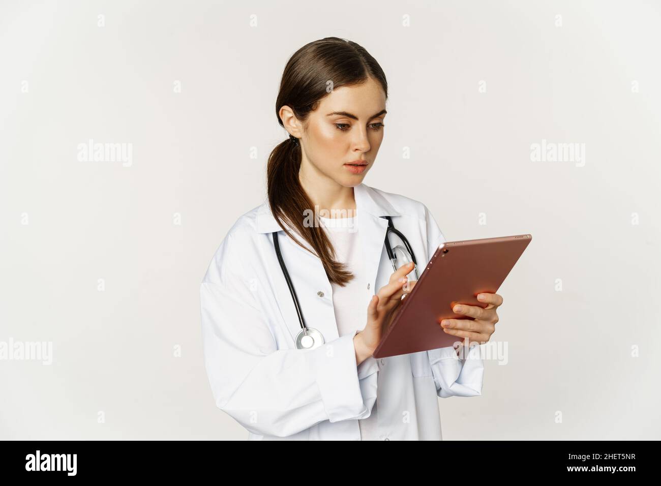 Woman doctor looking concerned at digital tablet, reading with worried ...
