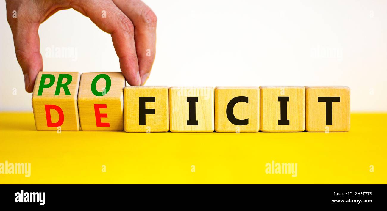 Proficit or deficit symbol. Businessman turns cubes, changes the word deficit to proficit ...