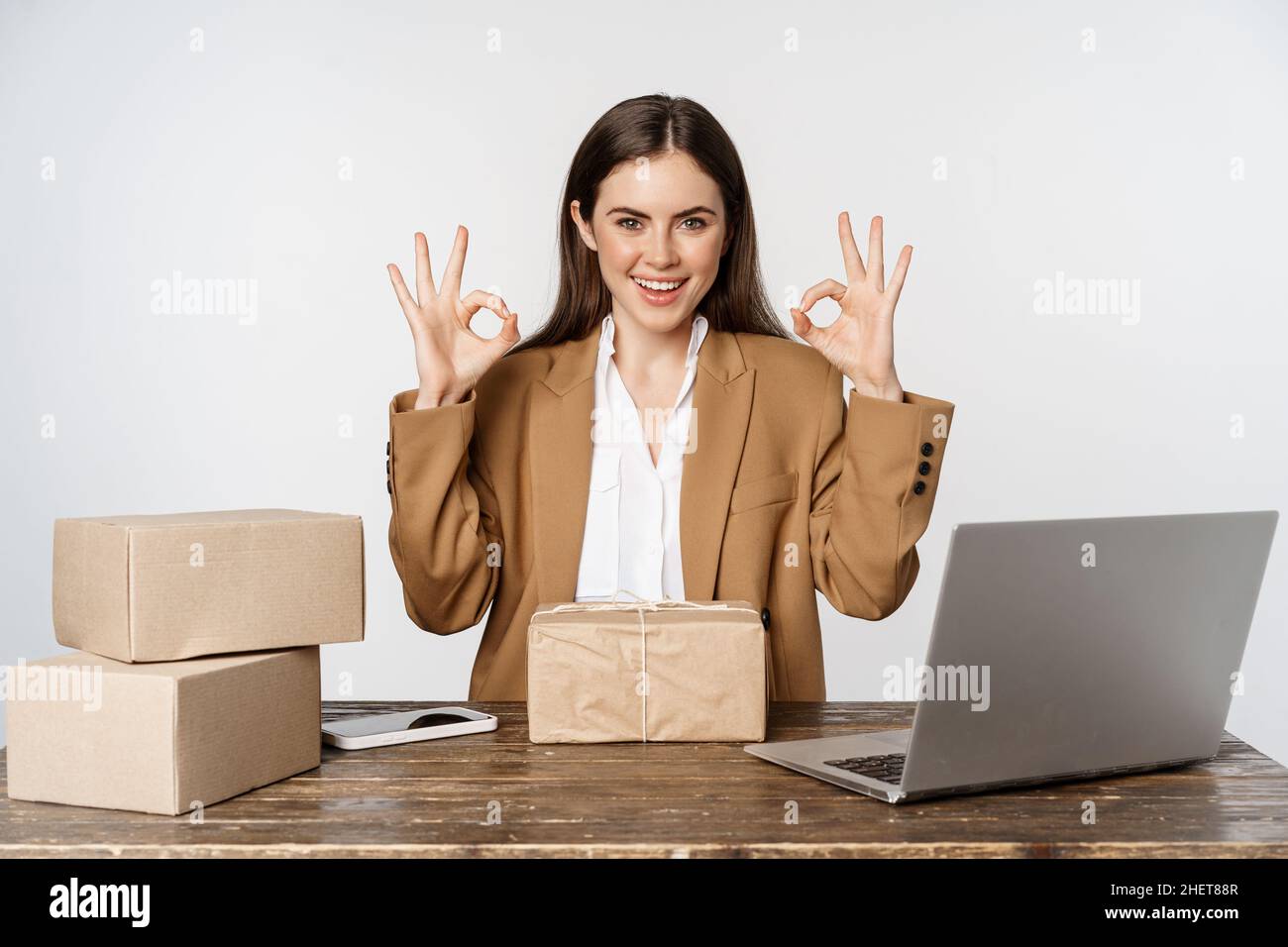 Woman small business owner, sitting at table with laptop, packing boxes, processing clients ...