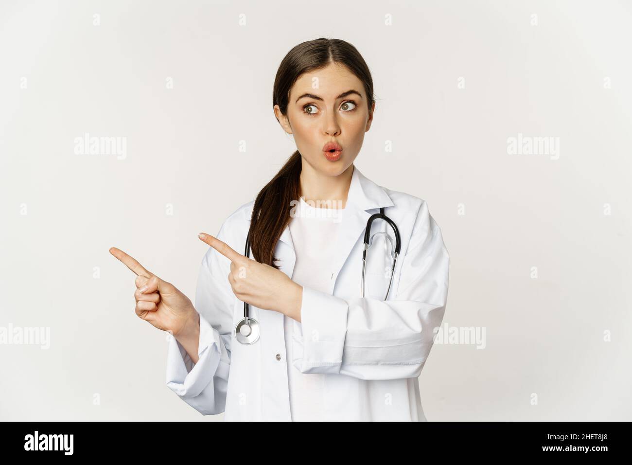 Surprised doctor, physician pointing fingers left and looking at logo ...