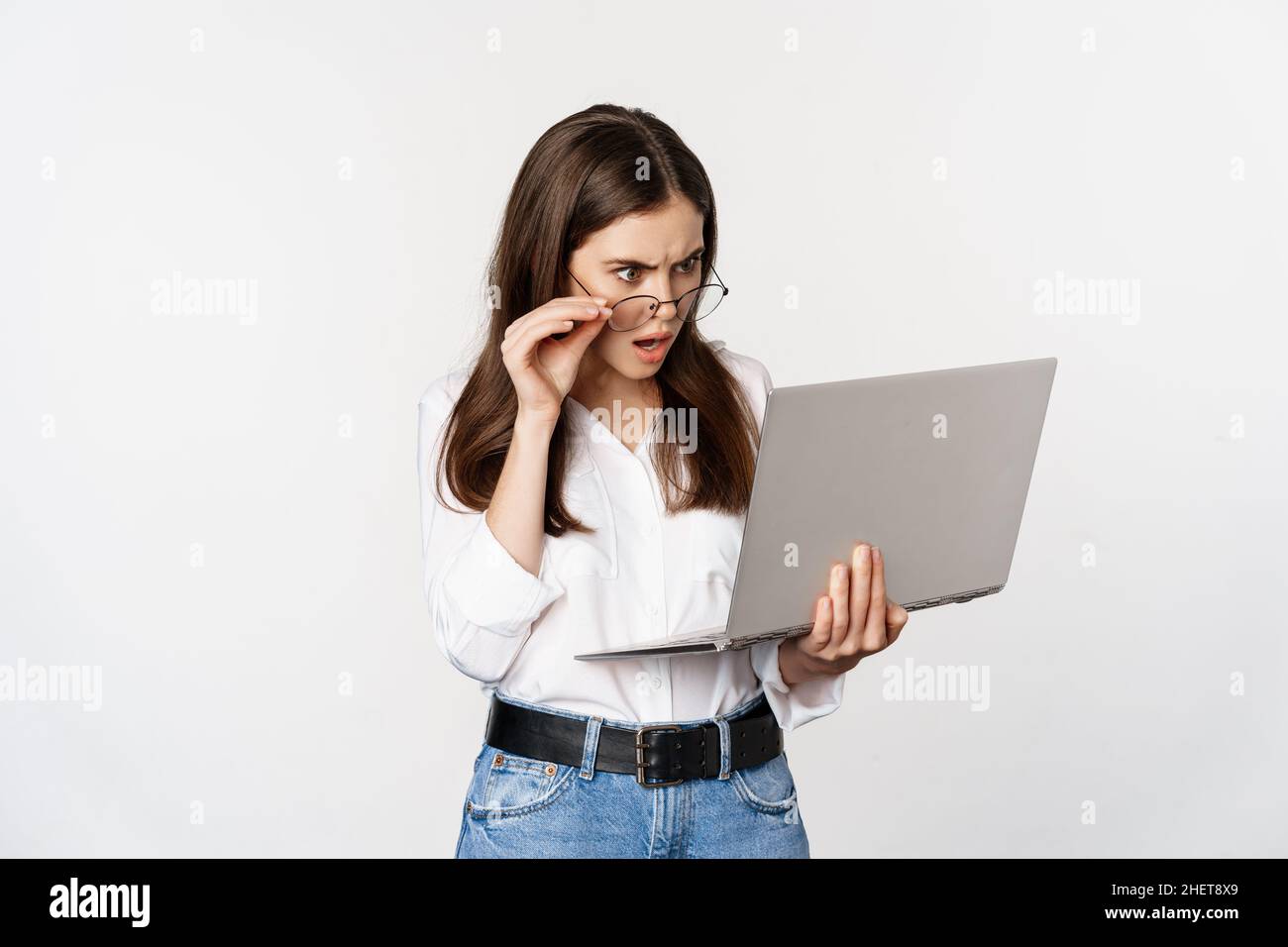 Shocked woman looking at laptop screen confused, stunned about smth on ...