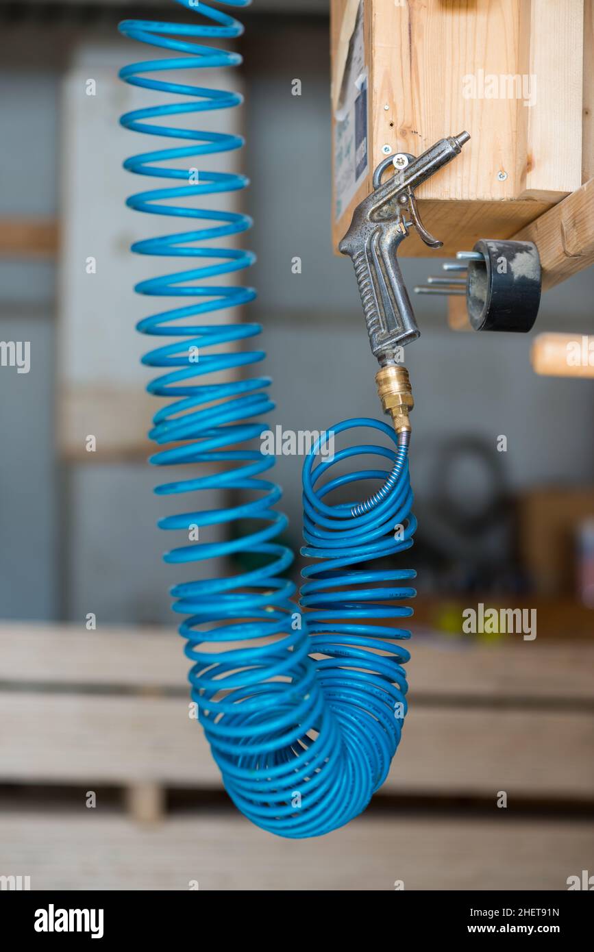 blue compressed pneumatic air hose with pistol hanging at screw Stock ...