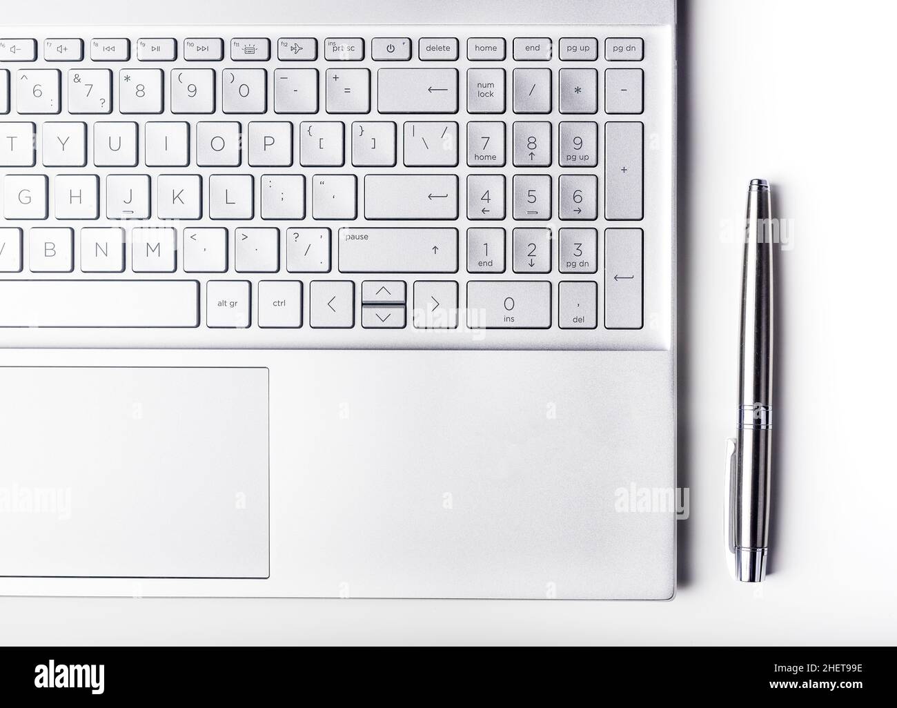 Laptop keyboard and pen of silver color, top view. Business and ...