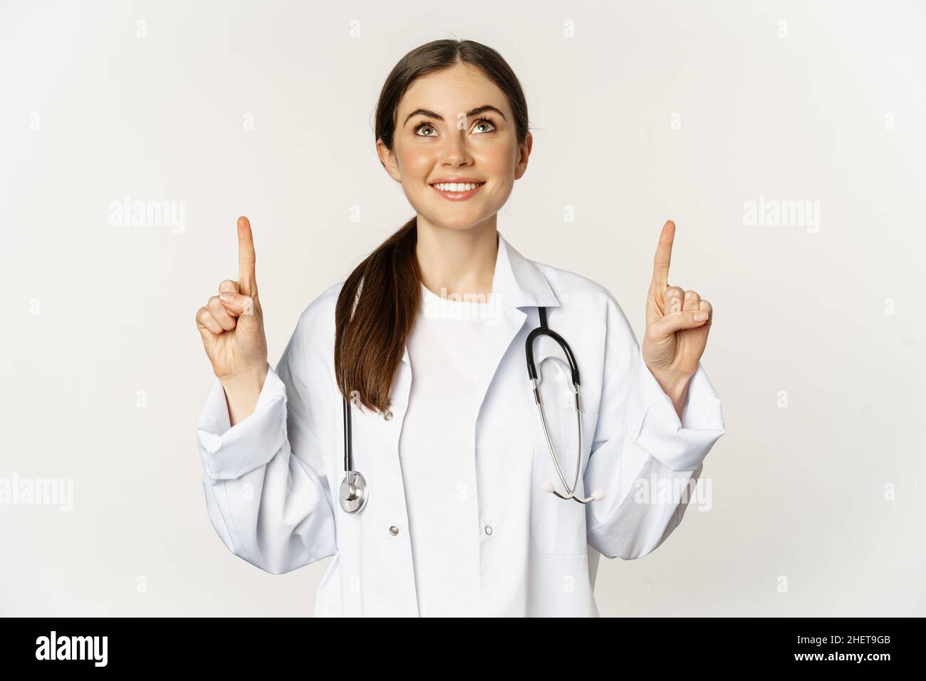 Happy beautiful doctor, female physician pointing fingers up, showing ...