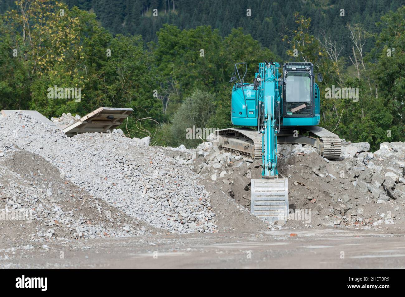 blue shovel digger on gravel heap in front of forest Stock Photo - Alamy