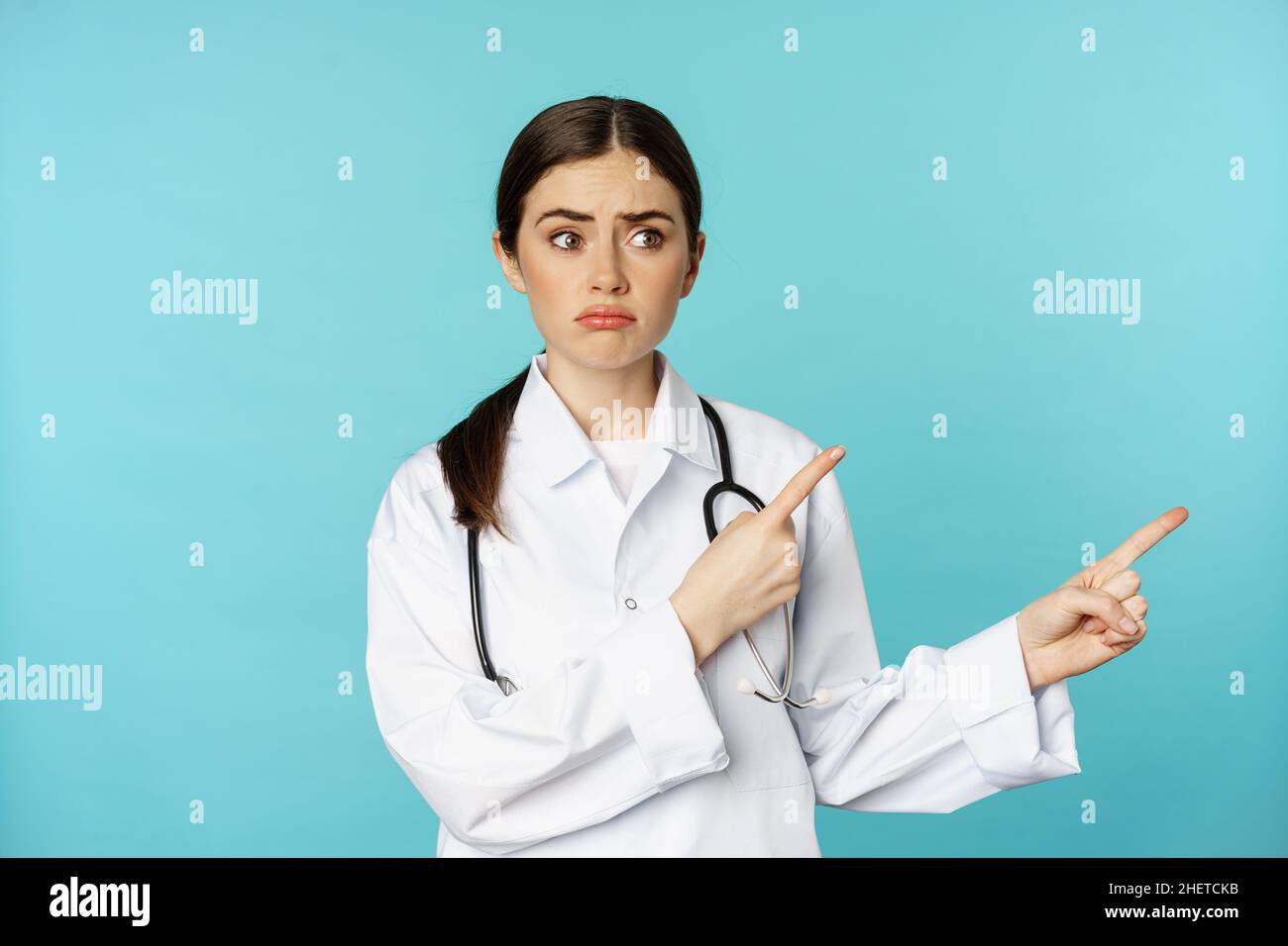 Portrait of disappointed doctor, woman medical worker pointing fingers ...