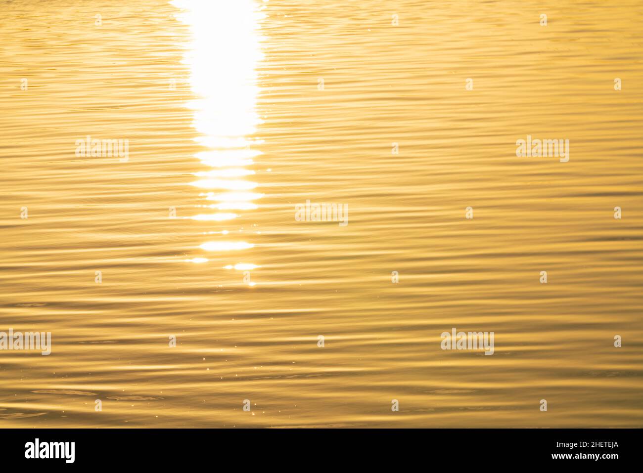 Ripples on surface of golden water with rising sun glow brightly ...