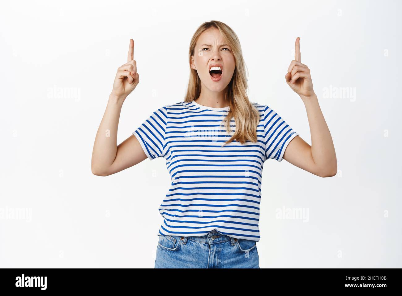 Angry blond woman complains, points and looks up with frustrated ...