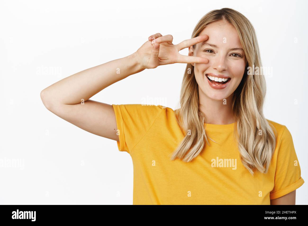 Portrait of smiling happy blond girl showing peace, v-sign gesture and ...