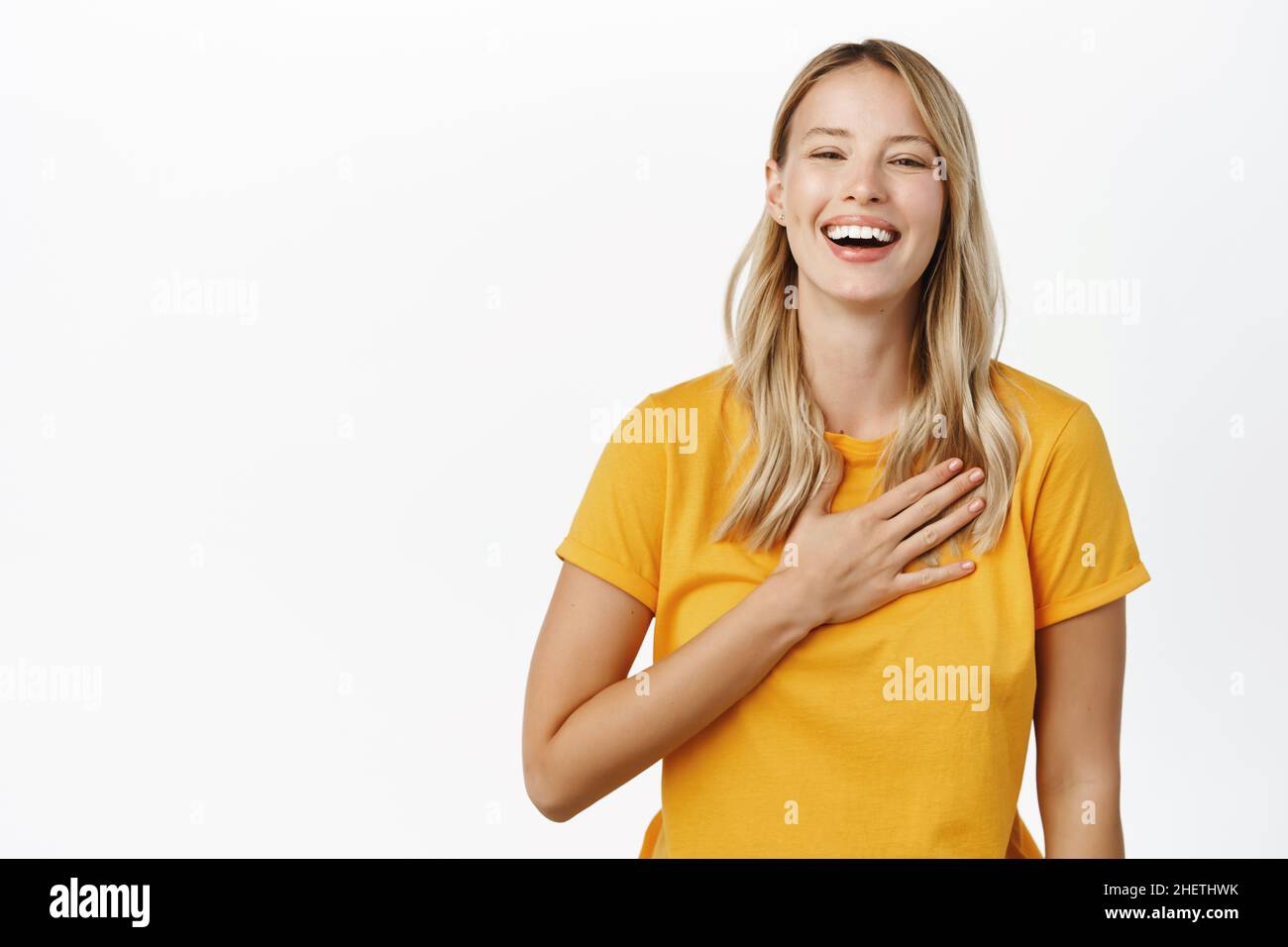 Smiling beautiful modern girl laughing, holding hand on heart ...