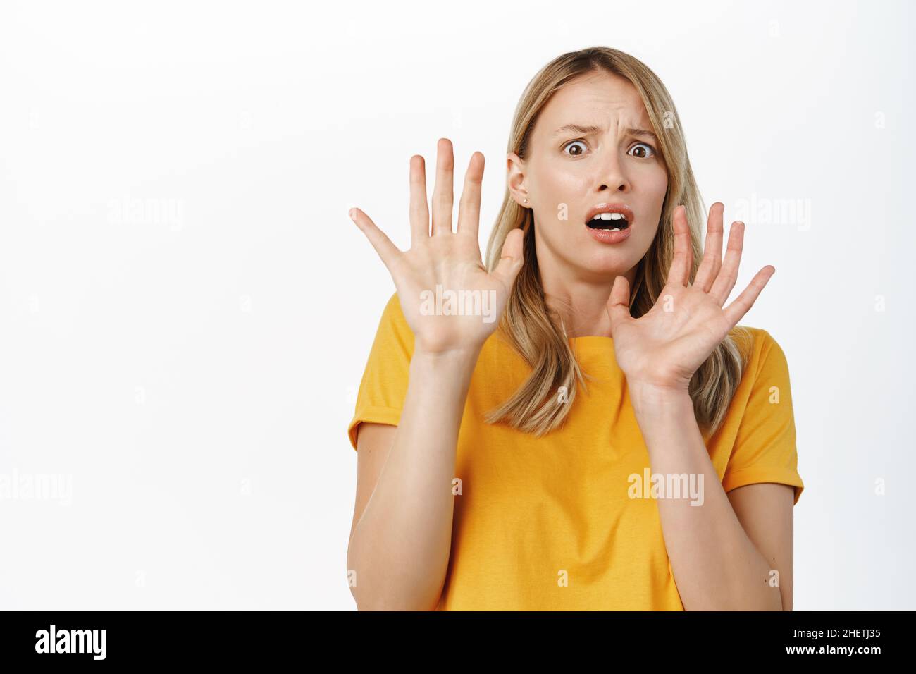 Portrait of scared young woman screaming, raising hands up frightened ...