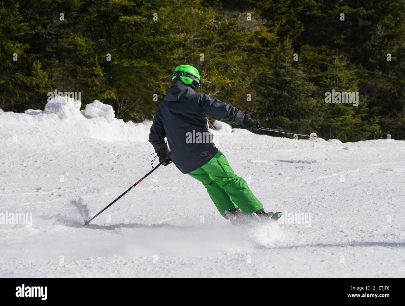 Back view of the skier going downhill on a fresh powder slope. Motion ...