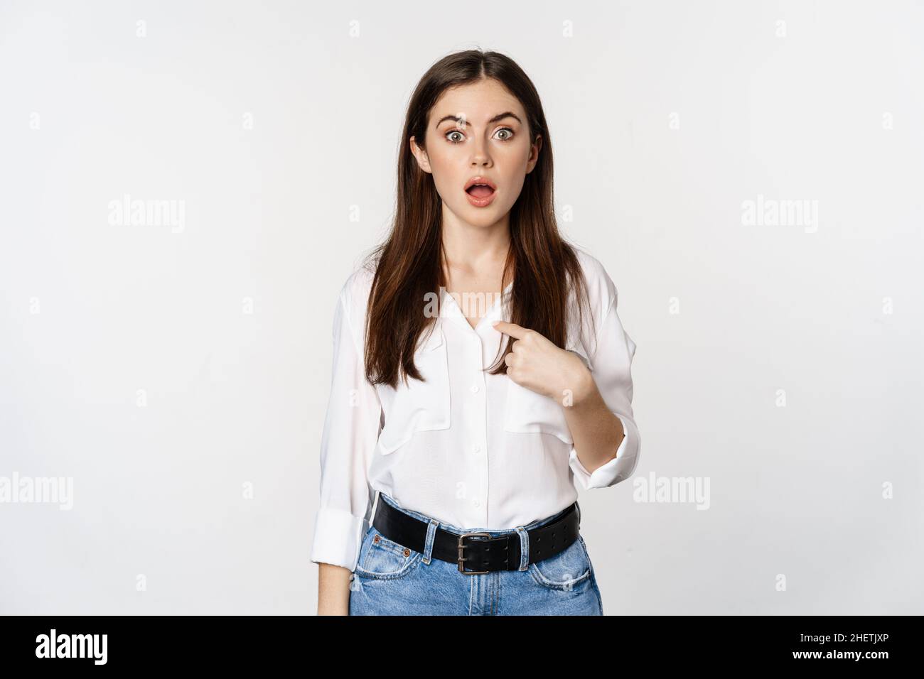 Portrait of young woman pointing at herself with disbelief, surprised ...