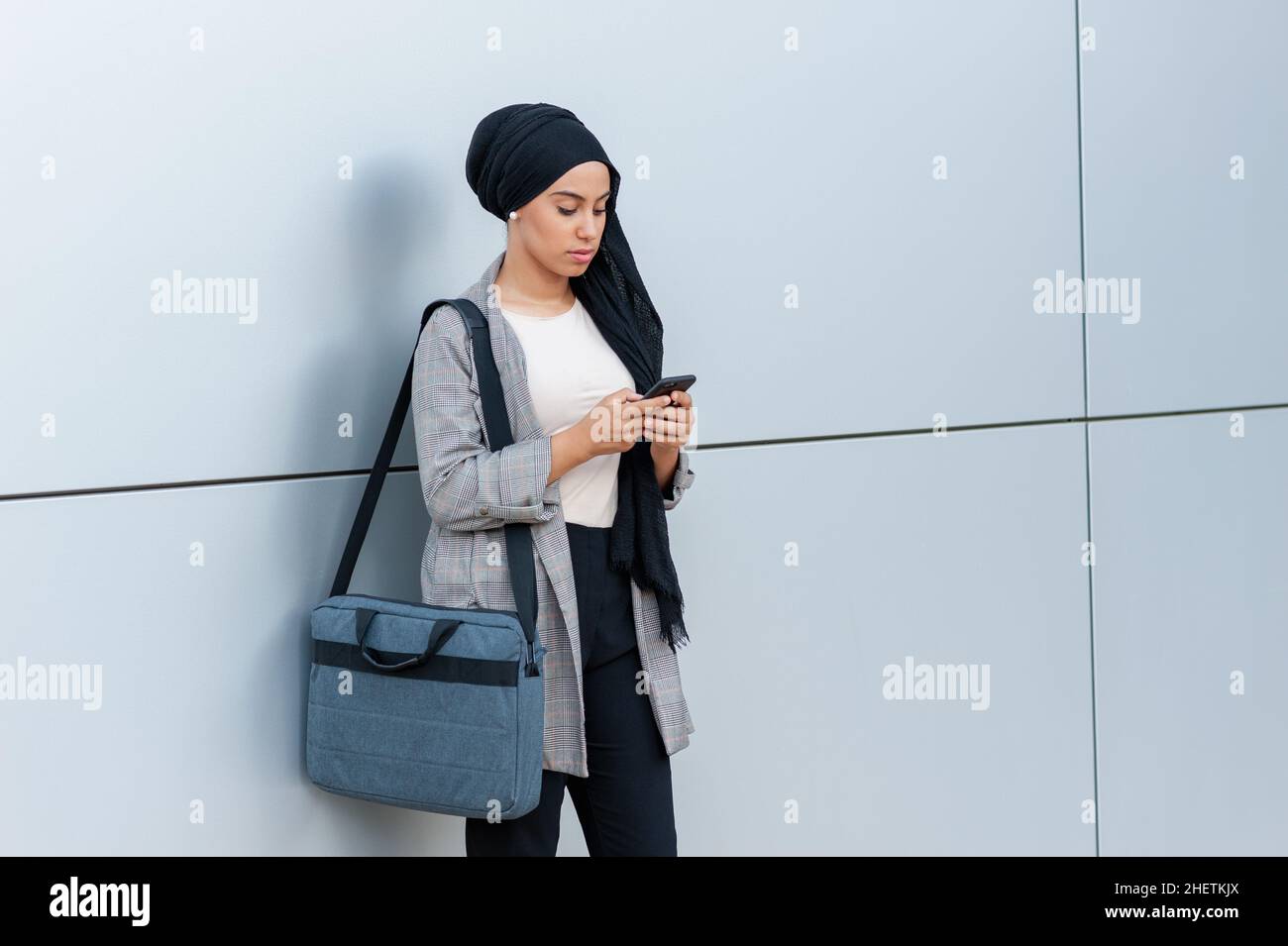 Front view of a muslim woman wearing a headscarf and holding her purse ...