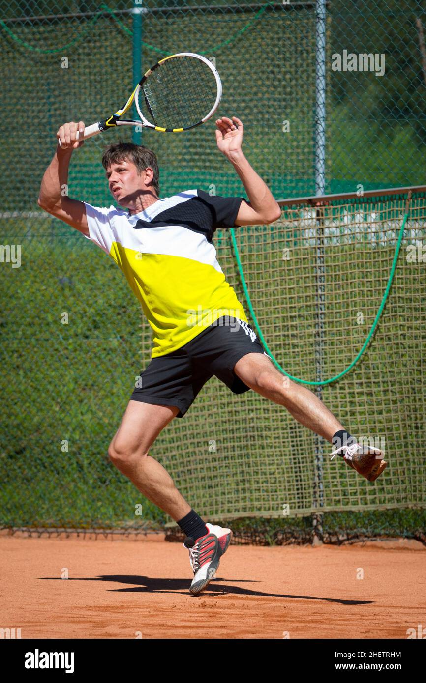 tennis player jumps after playing forehand ball Stock Photo - Alamy