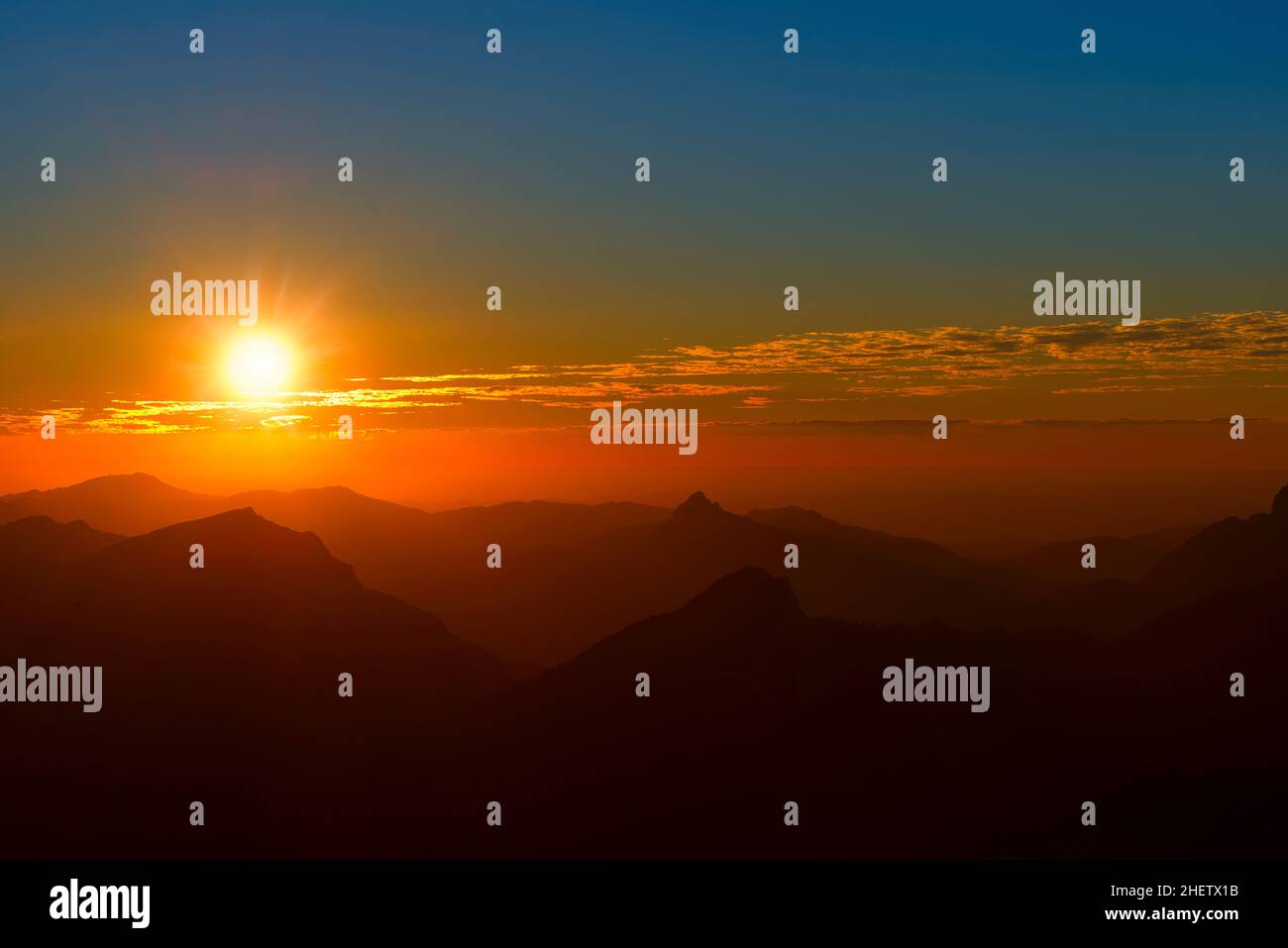 sunset between mountains and clouds with red sky Stock Photo - Alamy