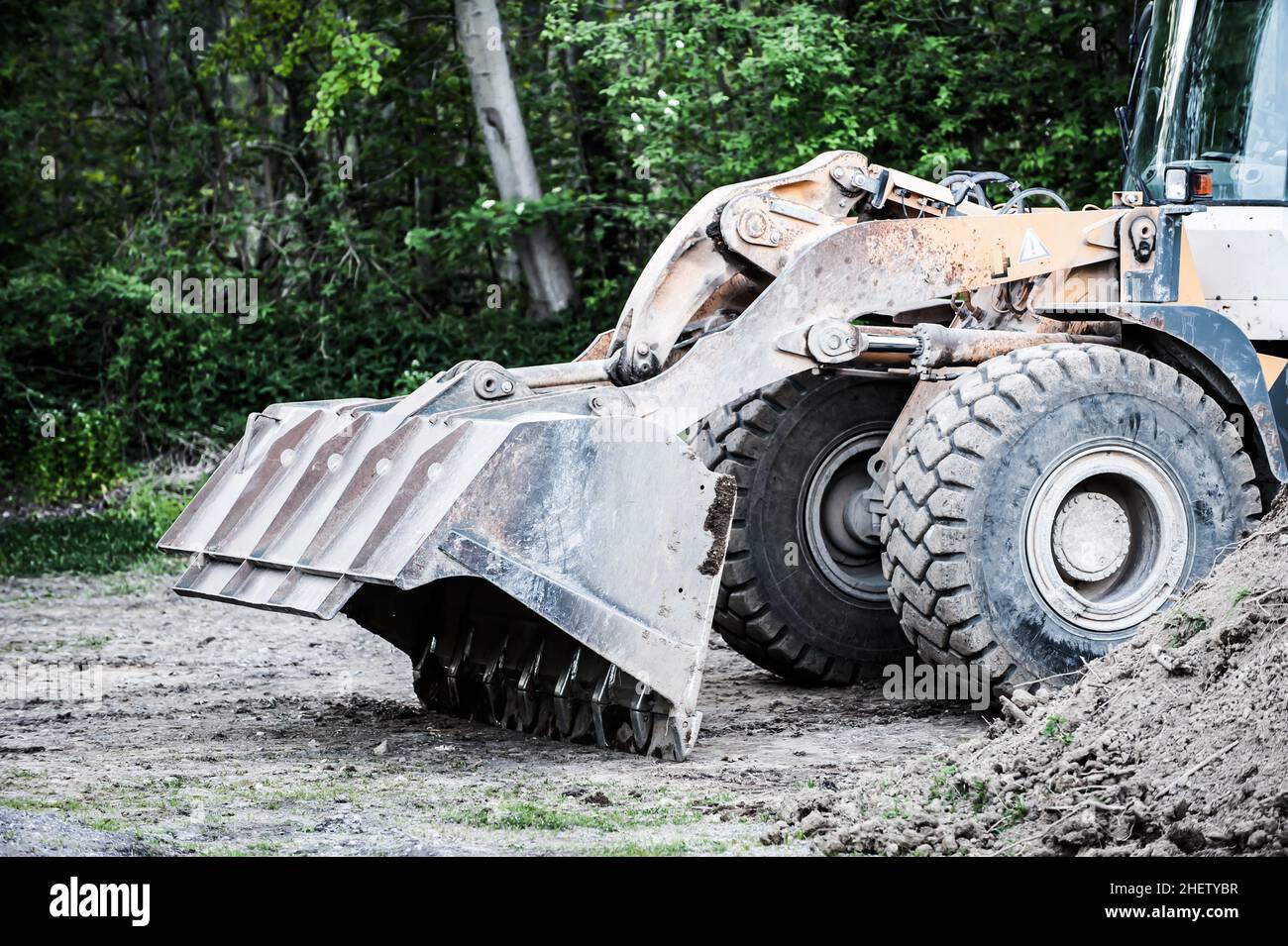 wheel loader stands at building site in front of forest Stock Photo - Alamy