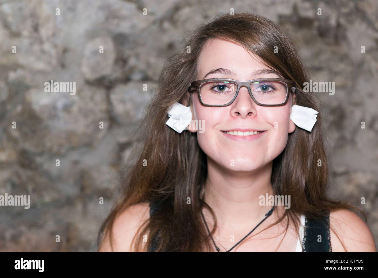 Pretty geek girl with eyeglasses and ear plugs in her ears Stock Photo ...
