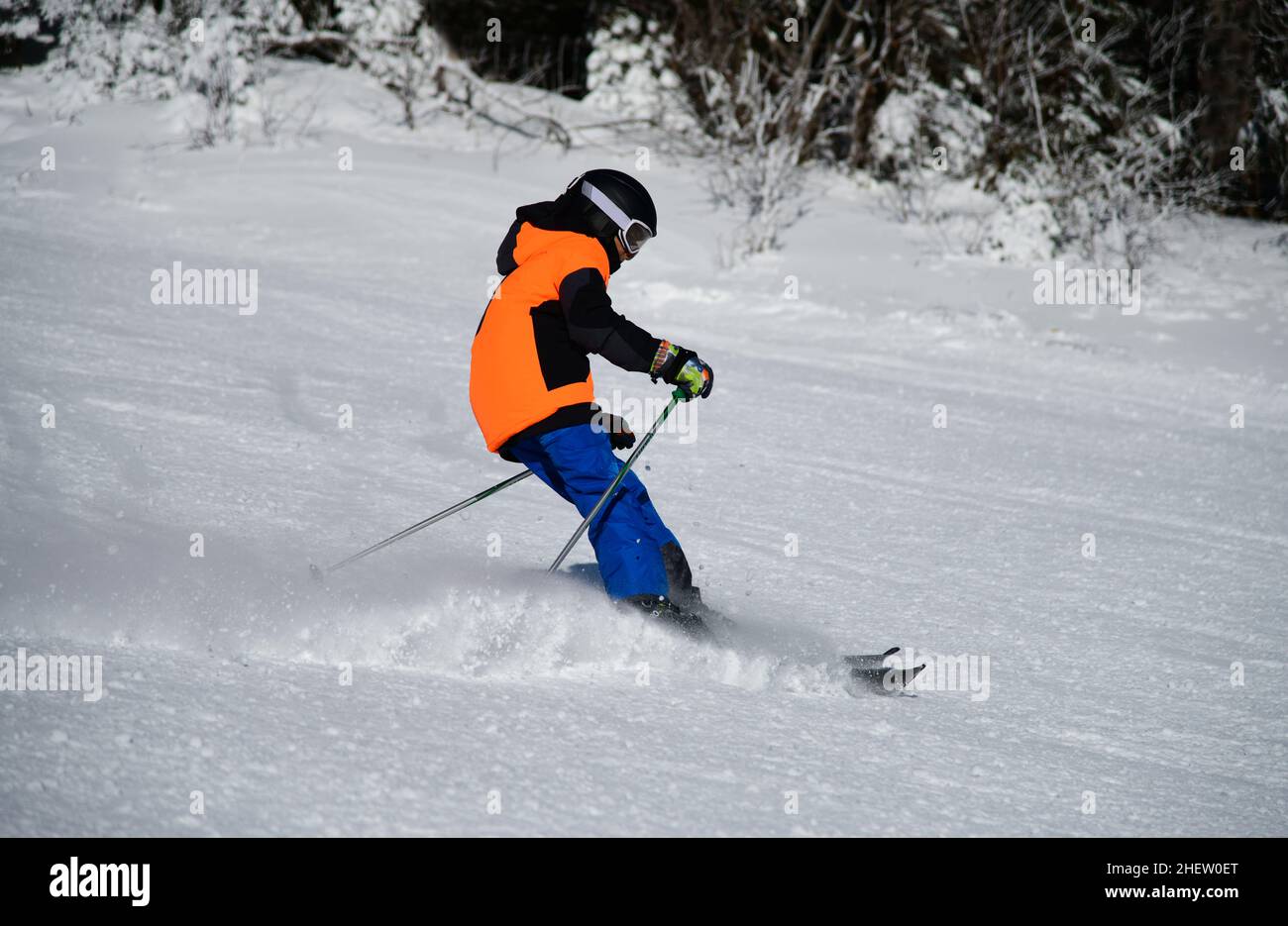 Action photo of skier in bright outfit going down the slope leaving ...