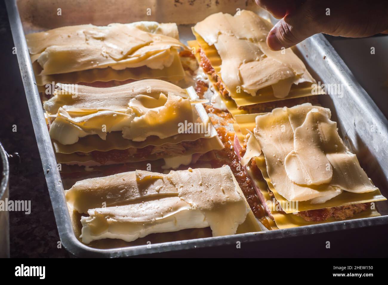 lasagna in an aluminum pan, spatula taking a piece of the pan ...