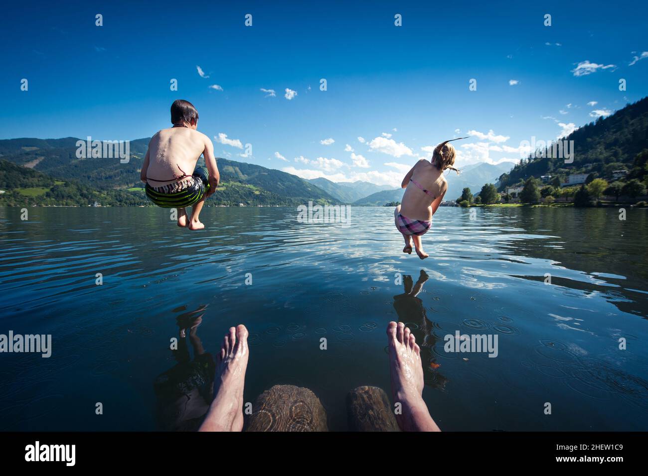 kids jumping into blue lake on summer day Stock Photo - Alamy