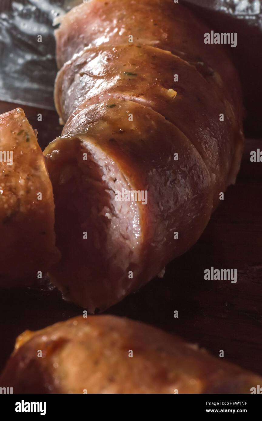 sausage sliced on a wooden board with pieces of cheese inside the ...
