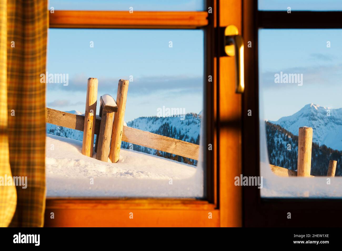 view through window of a hut with very much snow and mountains at a ...