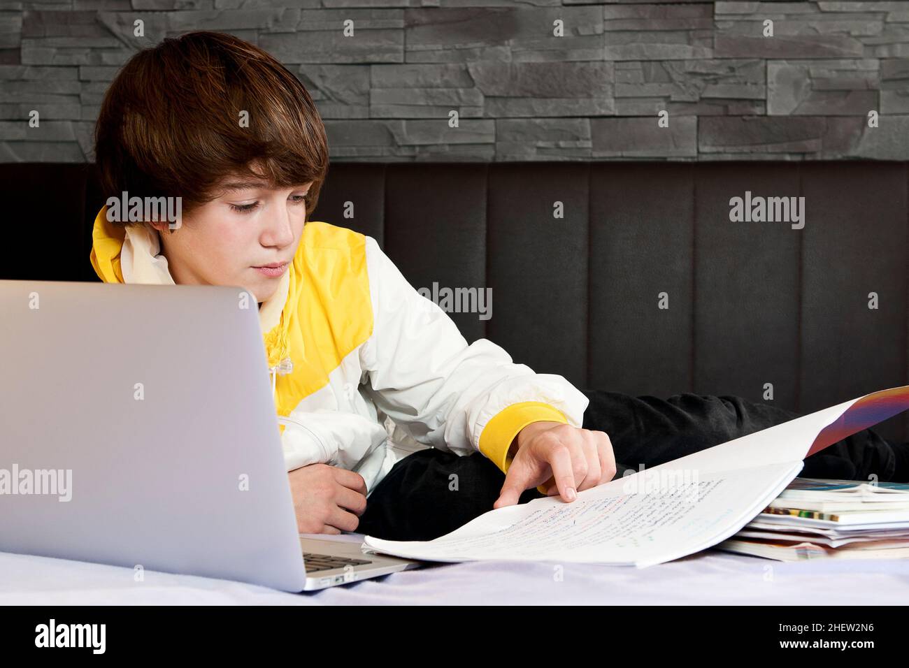 young school teenager makes his homework with notebook and some books ...