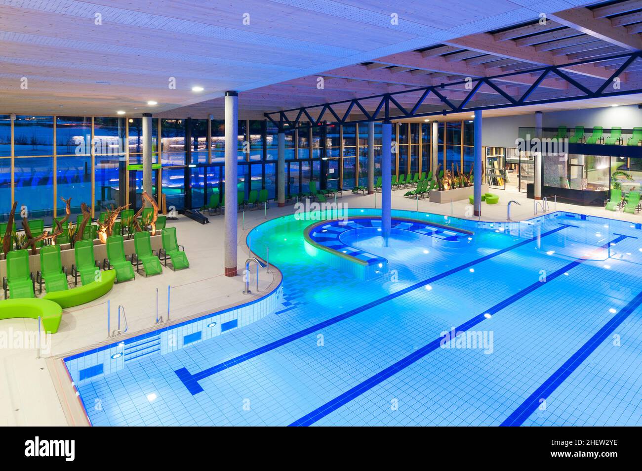 view from the top of a new swimming pool with green divans and lighted ...