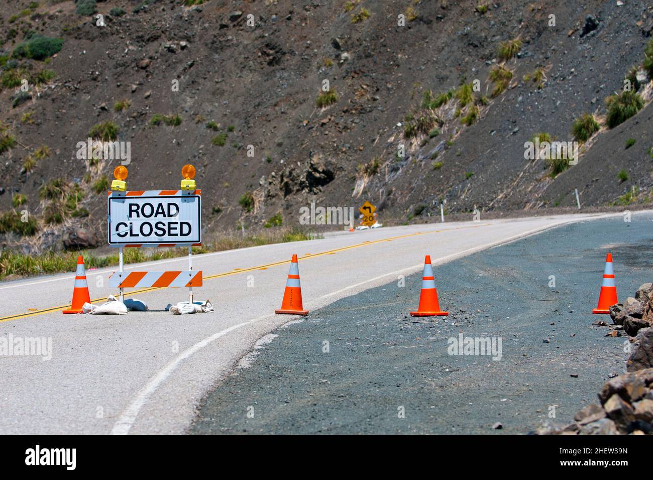 road closed sign on street with orange traffic cones and blinking ...
