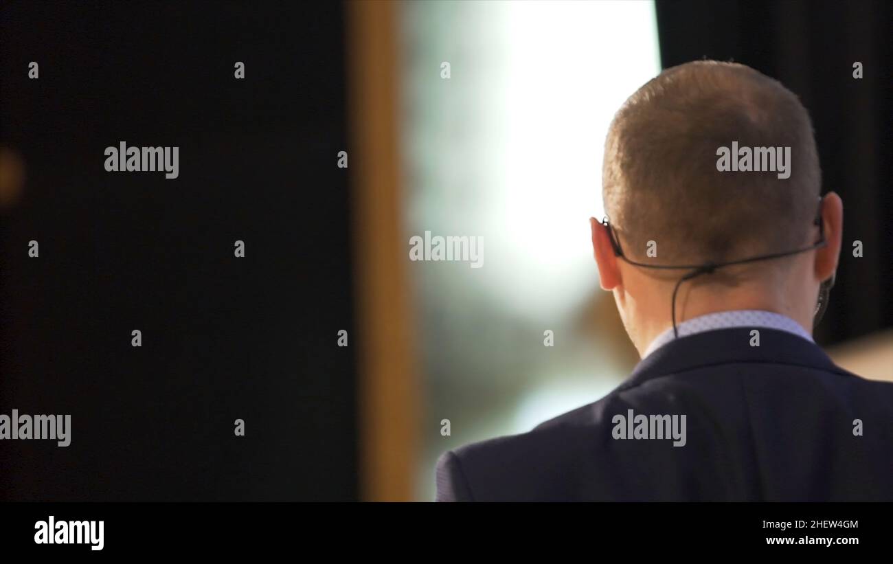 Rear view of speaker in suit giving a talk on corporate Business ...