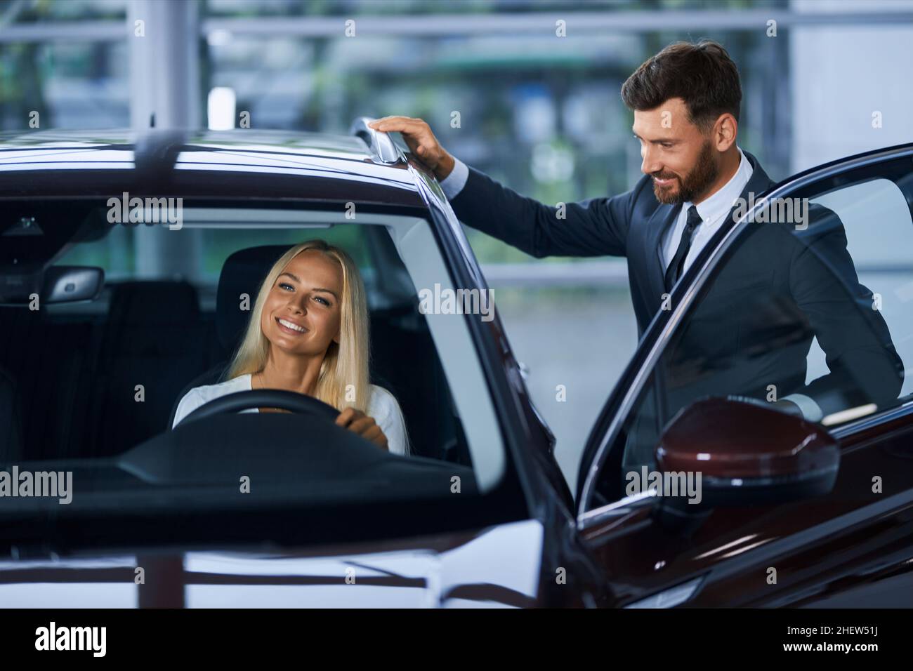 Professional salesman in suit showing to female customer various auto ...