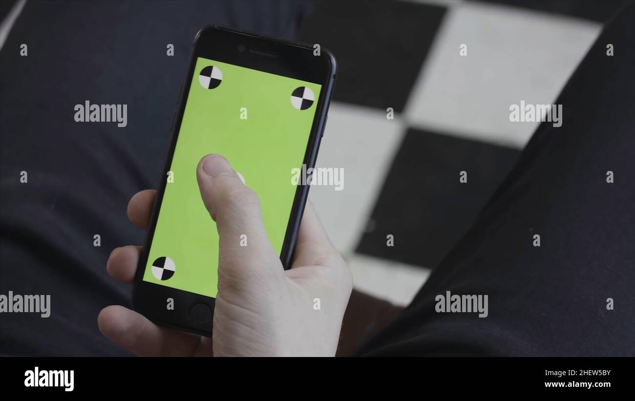 Man hands using mobile smartphone with green screen, over the shoulder ...