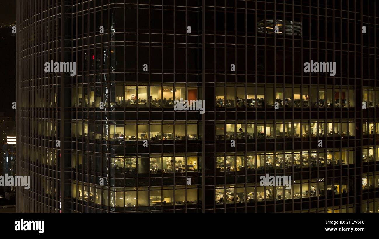 Close up for skyscraper windows glow at night and people inside, night ...