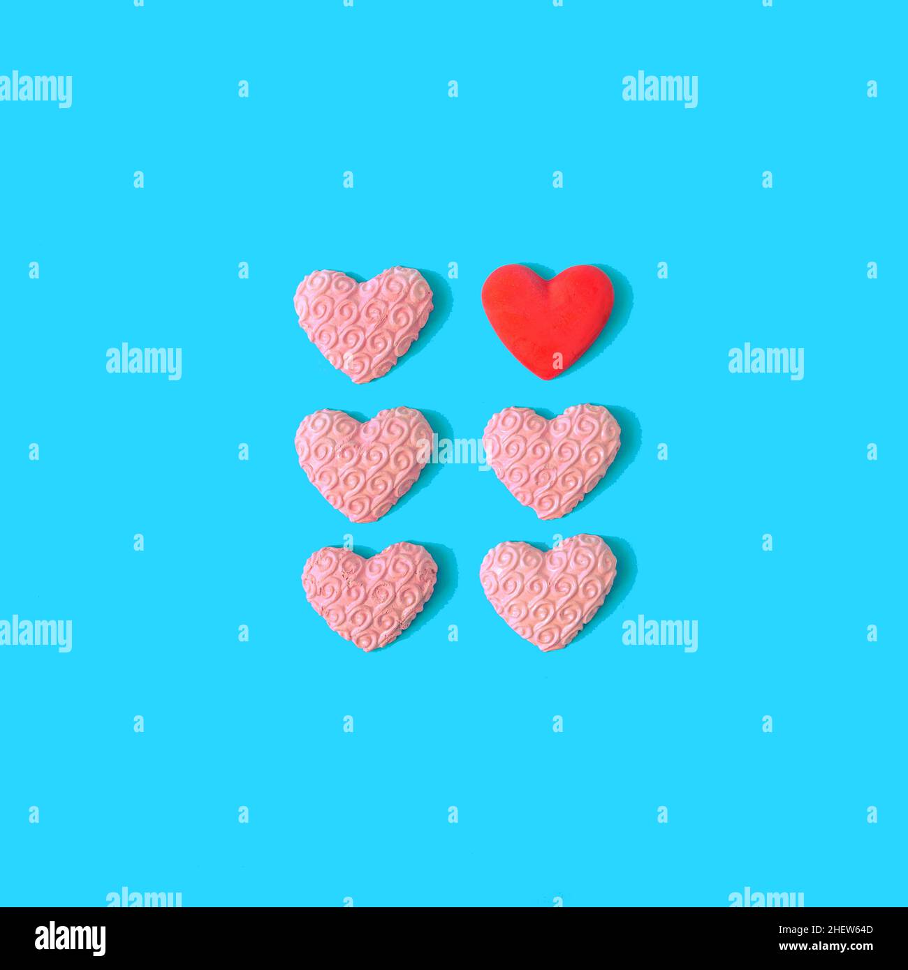 Five pastel pink hearts and one red neatly aligned on bright blue ...